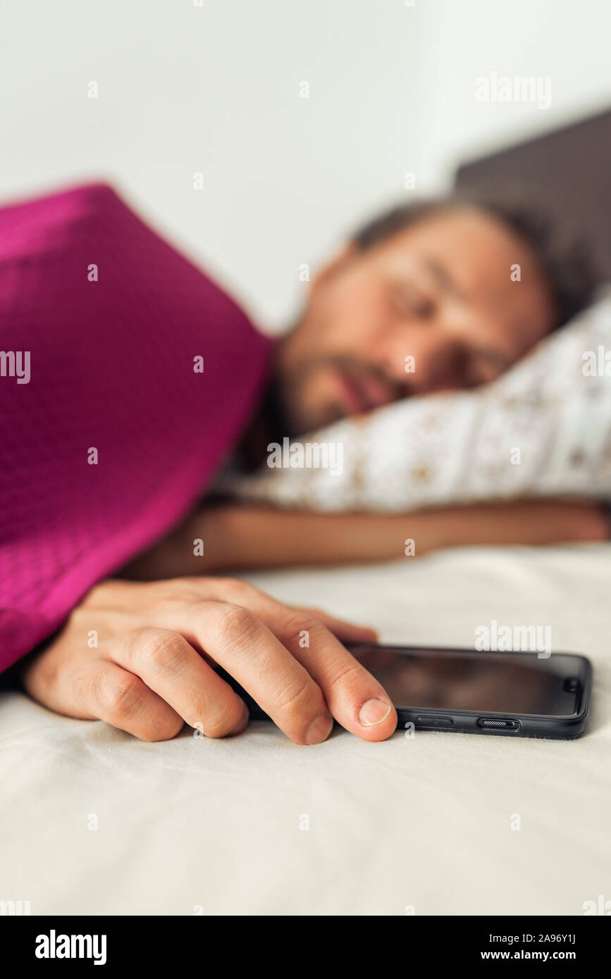 Sleeping young handsome man while holding his mobile phone. Screen on ...