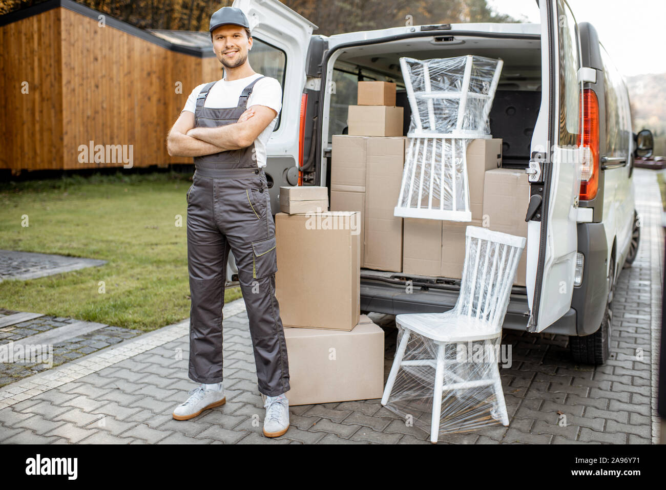 Portrait of a handsome delivery man in uniform standing near a cargo ...