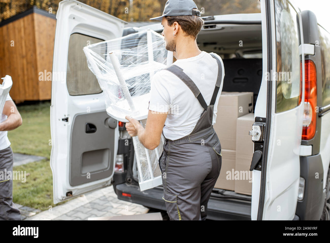 Delivery company employees unloading cargo van vehicle, delivering some ...