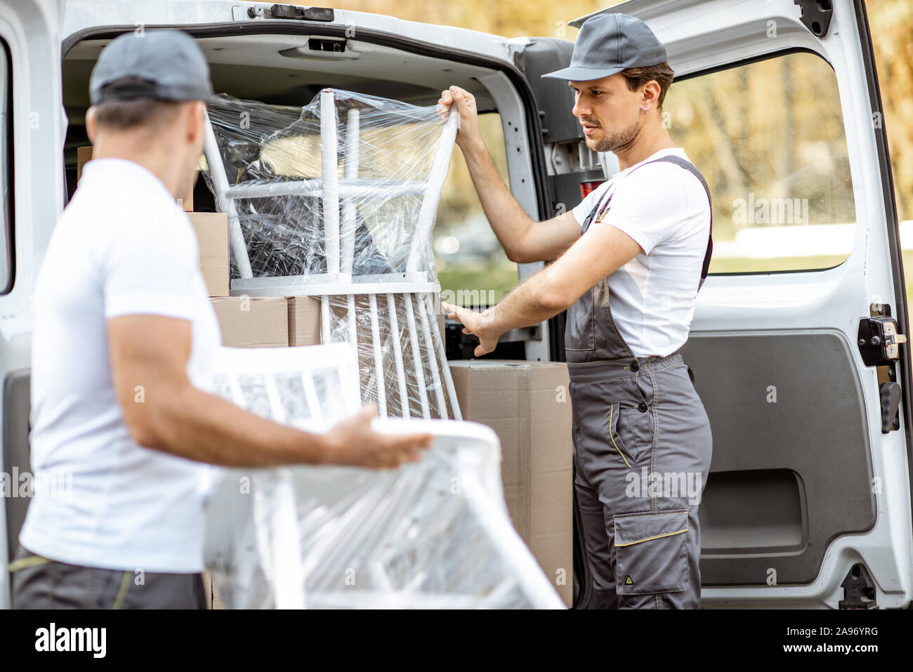 Delivery company employees unloading cargo van vehicle, delivering some ...