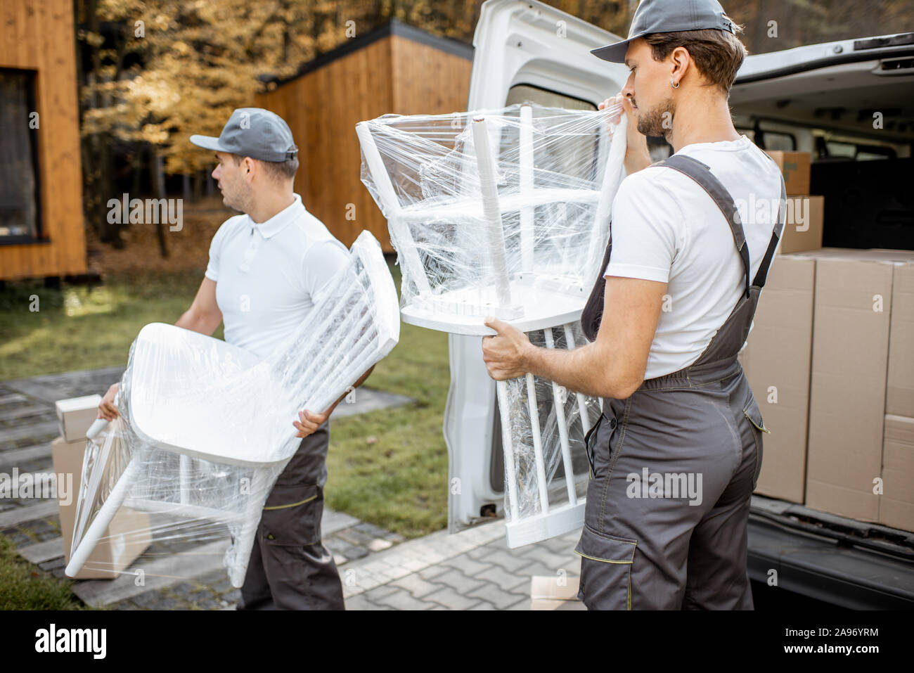 Delivery company employees unloading cargo van vehicle, delivering some ...