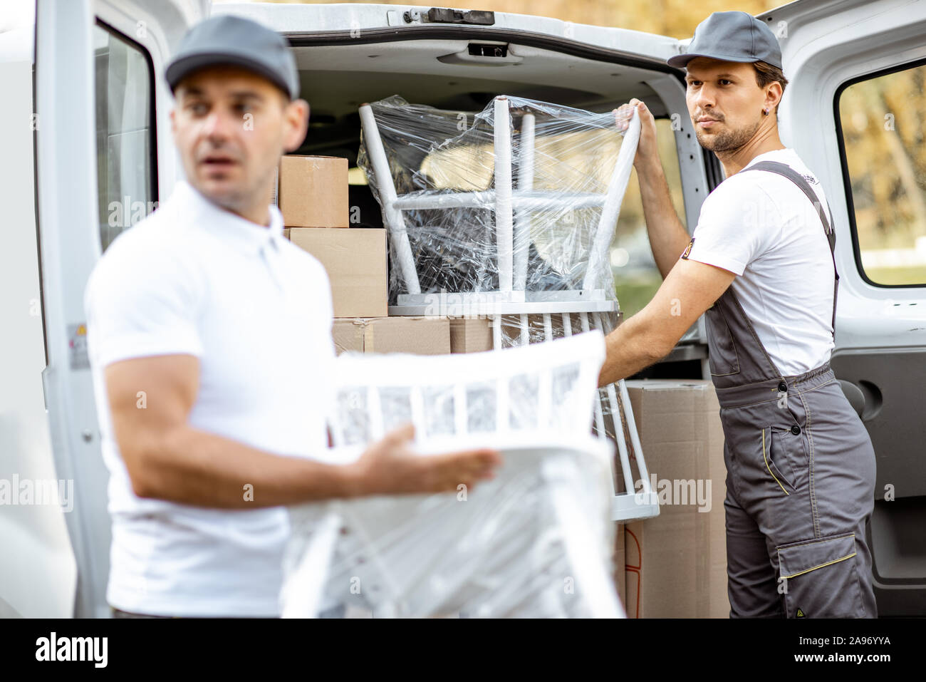 Delivery company employees unloading cargo van vehicle, delivering some ...