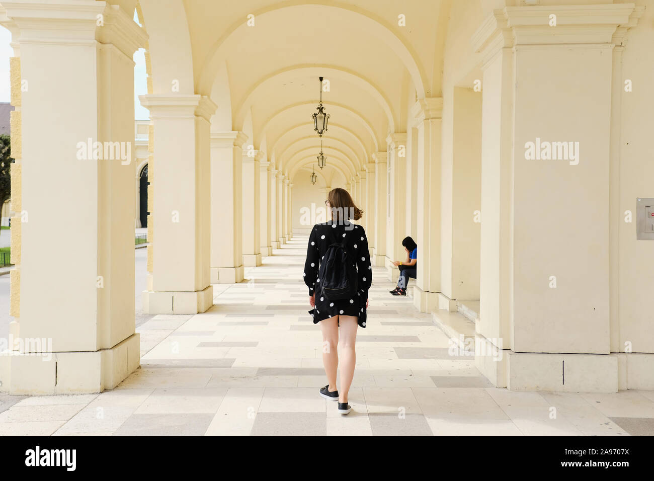 Young women tourists walks through the historic corridor in the Rococo ...