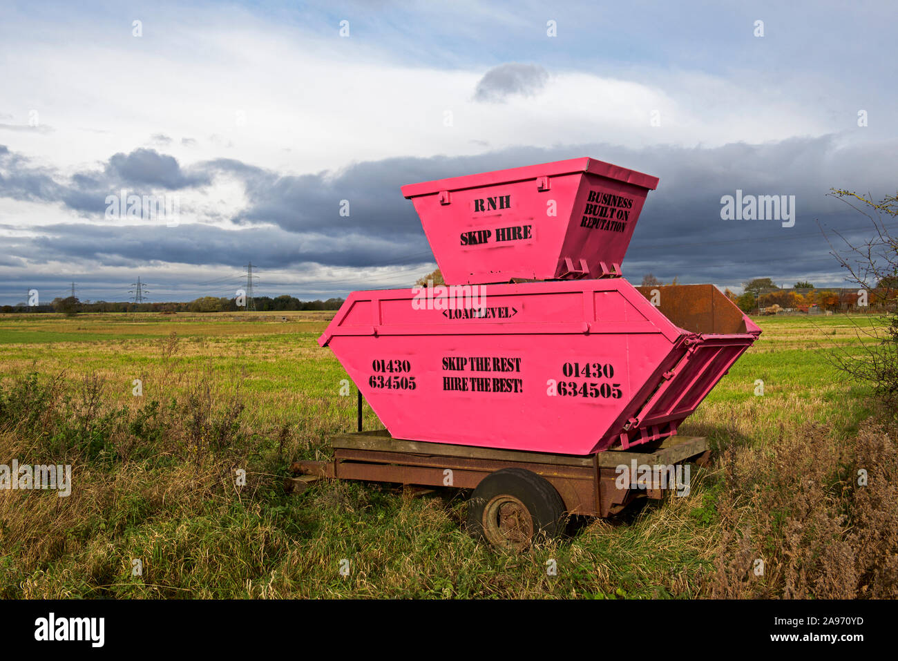 Pink rubbish skips on display in the corner of a field, to advertise a ...