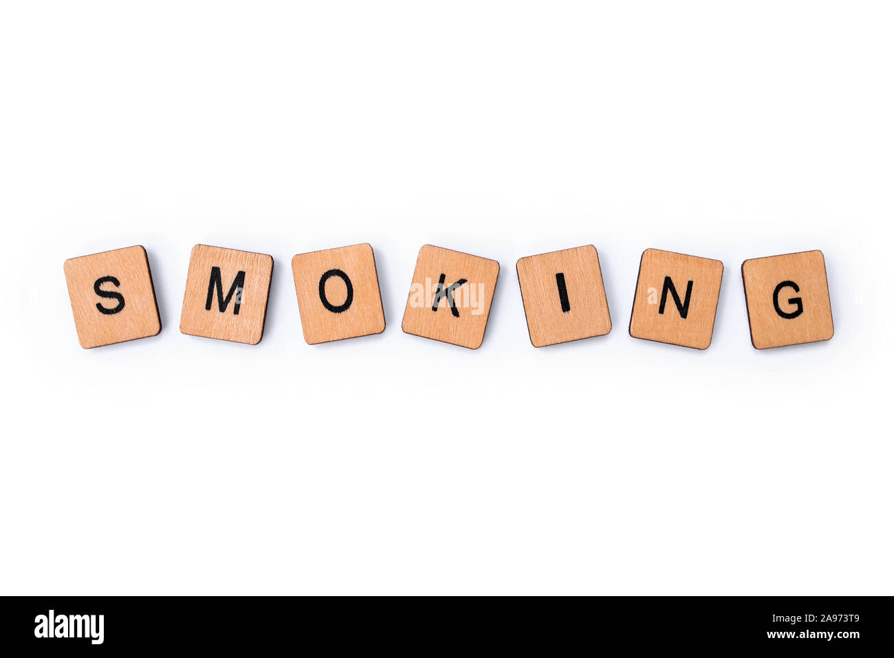 The word SMOKING, spelt with wooden letter tiles over a white ...