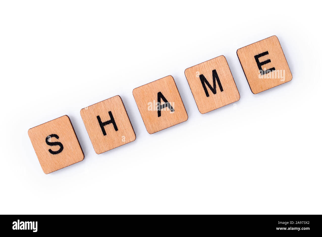 The word SHAME, spelt with wooden letter tiles over a white background ...