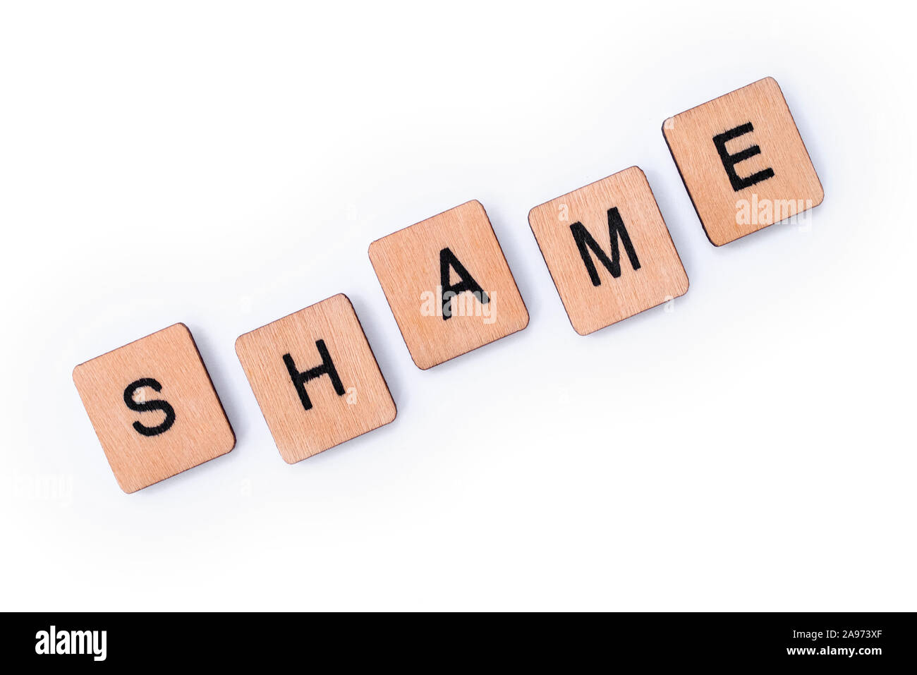 The word SHAME, spelt with wooden letter tiles over a white background ...
