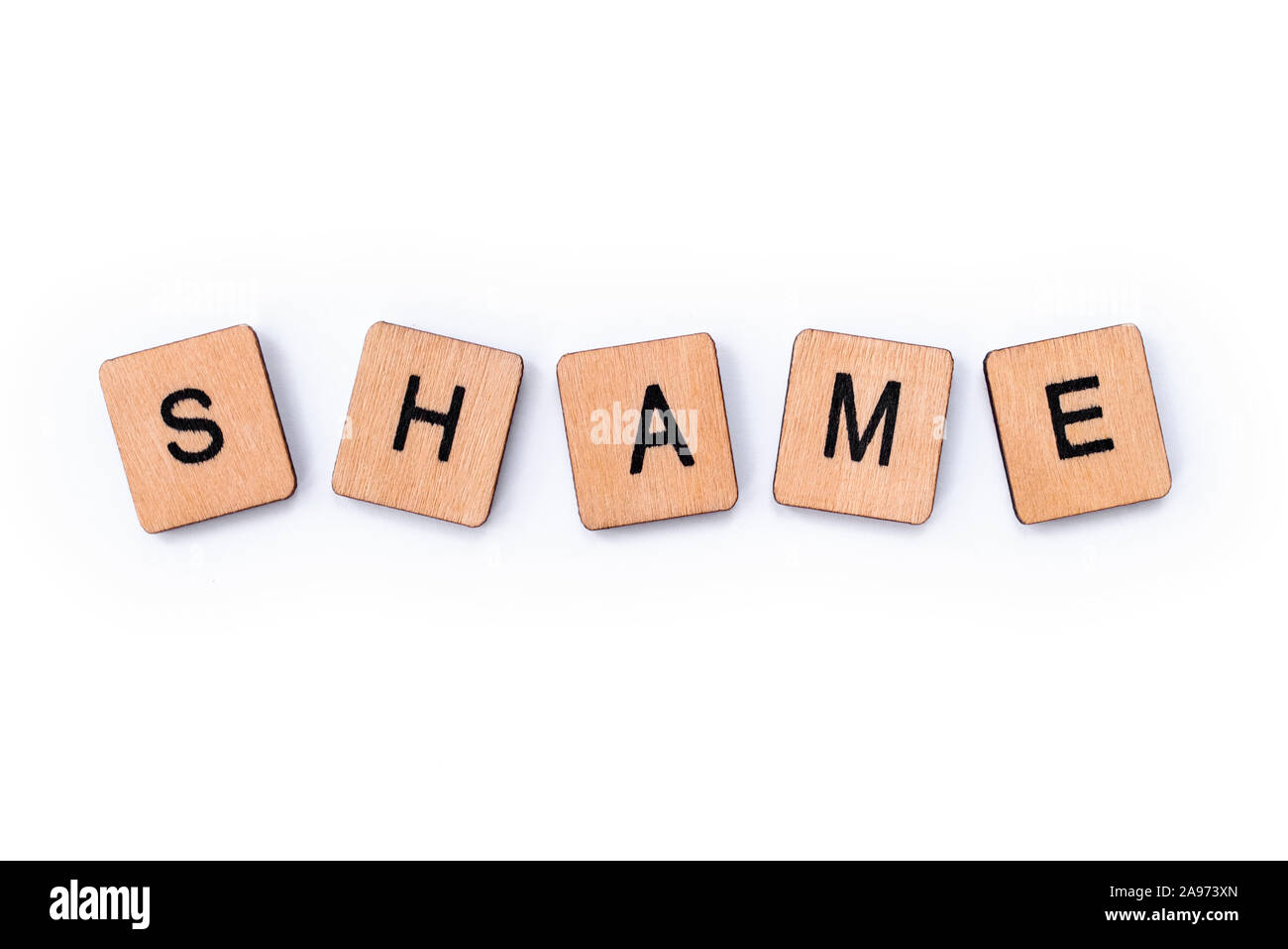 The word SHAME, spelt with wooden letter tiles over a white background ...