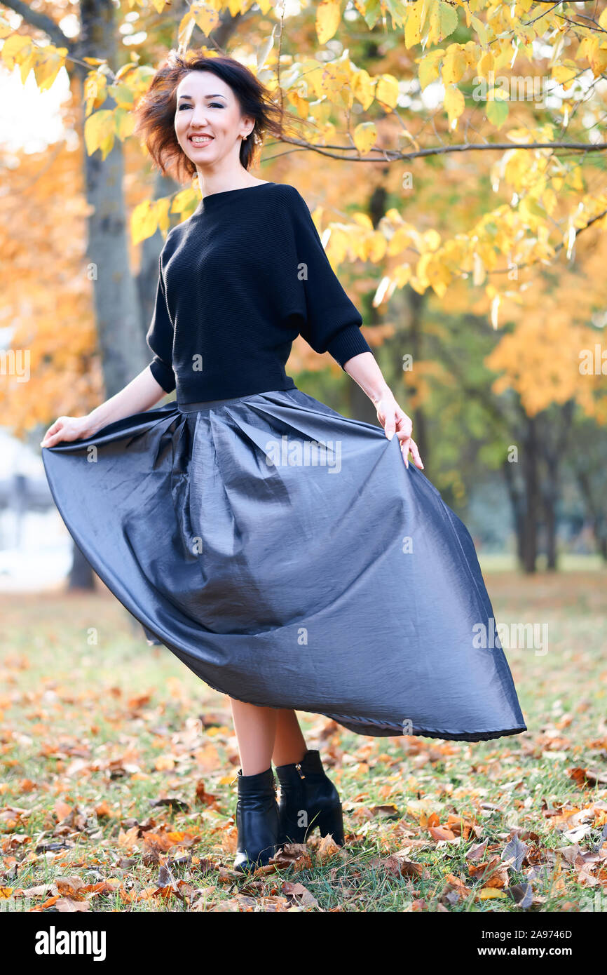 Beautiful elegant woman standing and posing in a city park in autumn ...