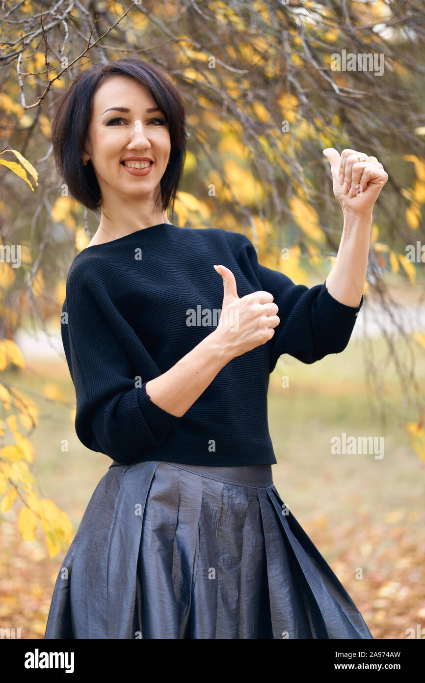 Beautiful elegant woman standing and posing in a city park in autumn ...