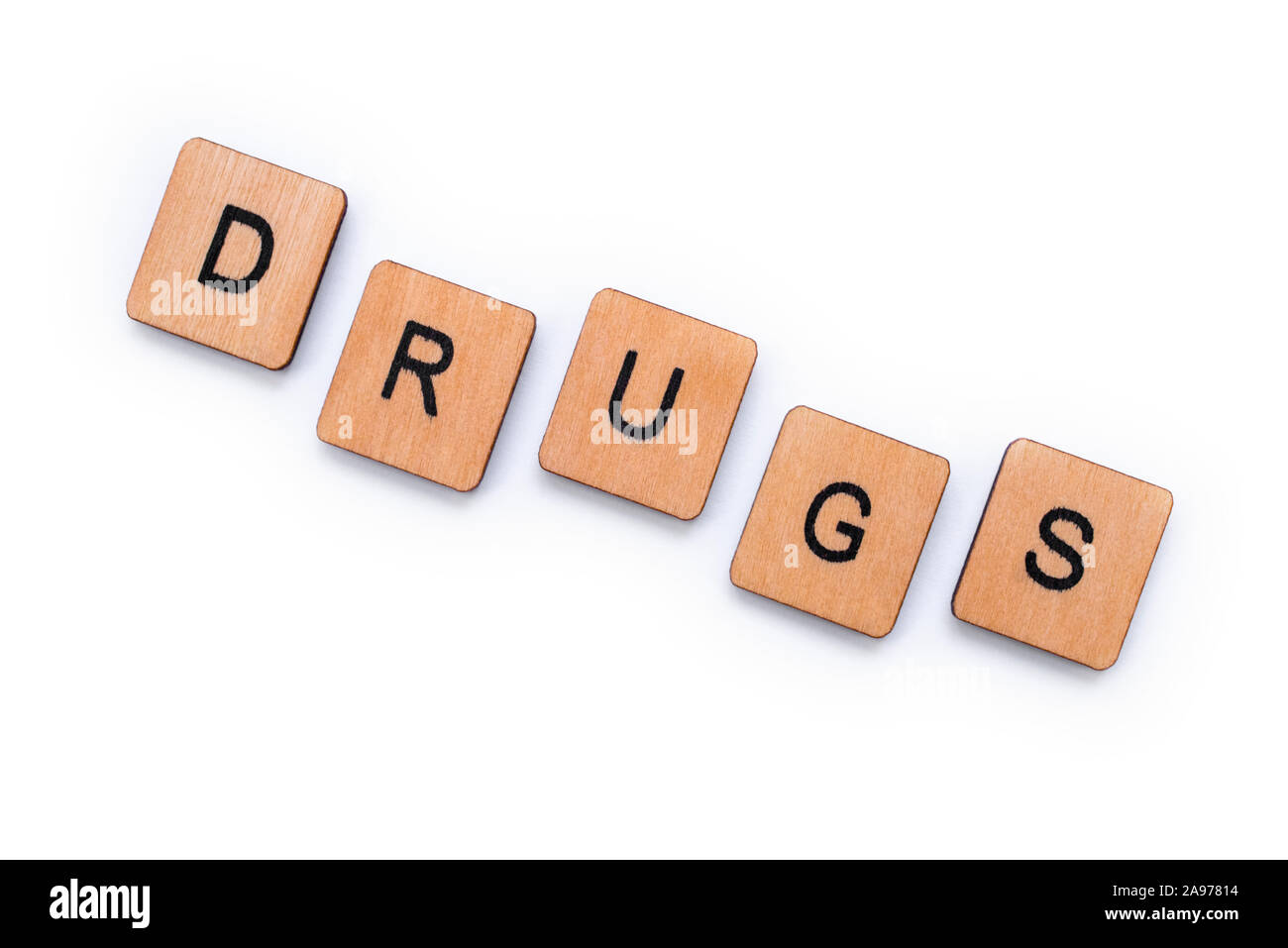 The word DRUGS, spelt with wooden letter tiles over a white background ...