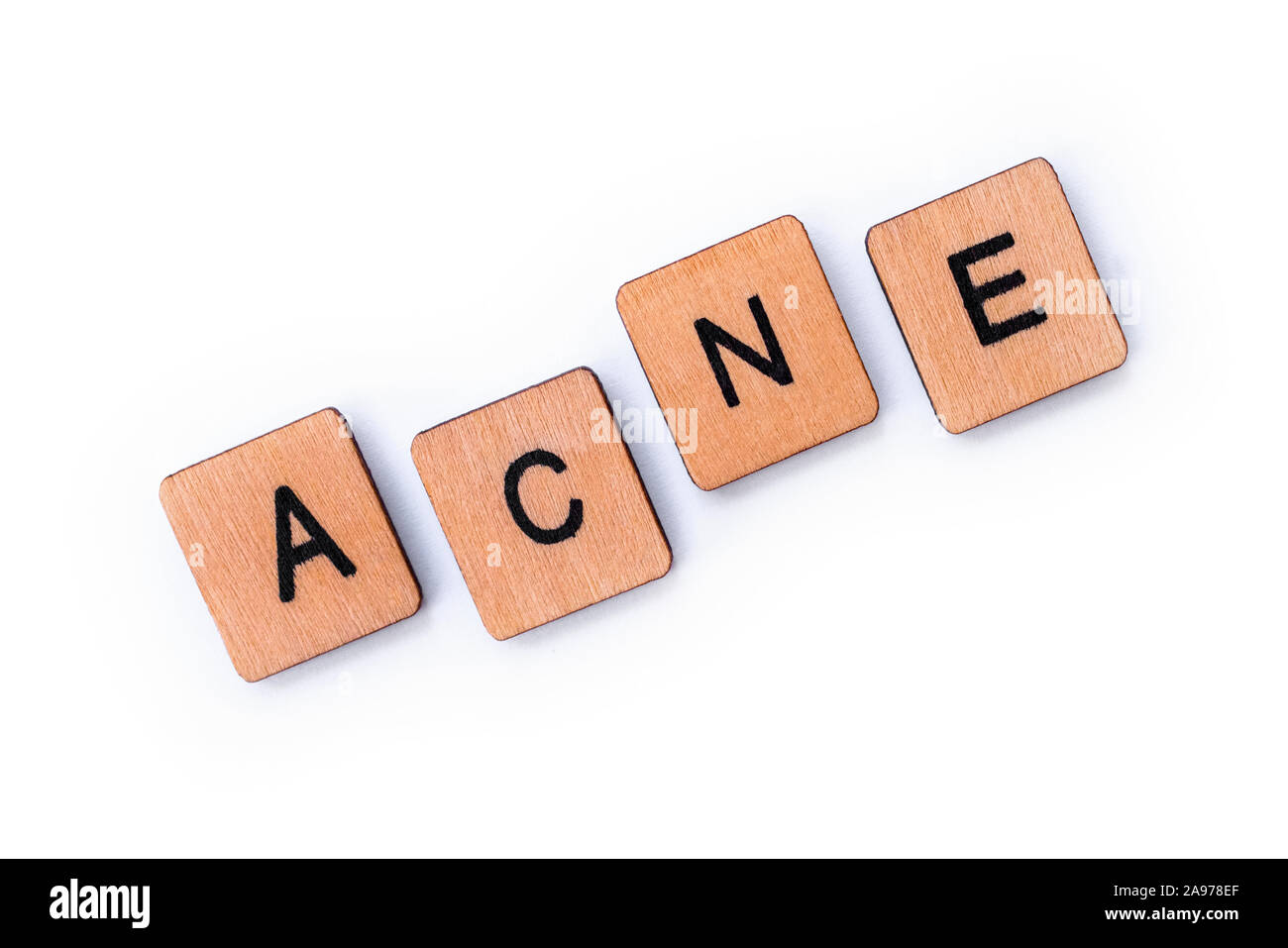 The word ACNE, spelt with wooden letter tiles over a white background ...