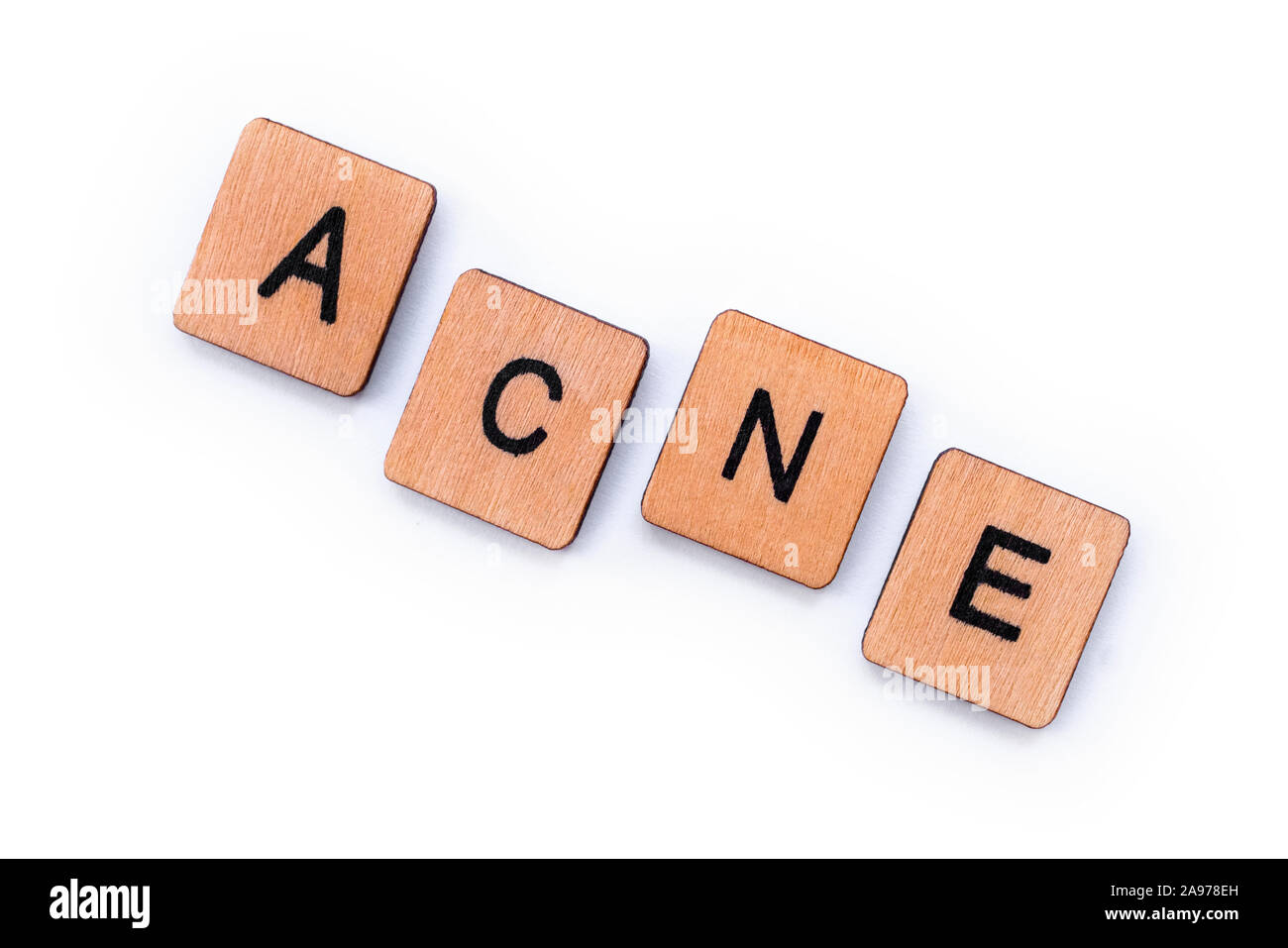 The word ACNE, spelt with wooden letter tiles over a white background ...