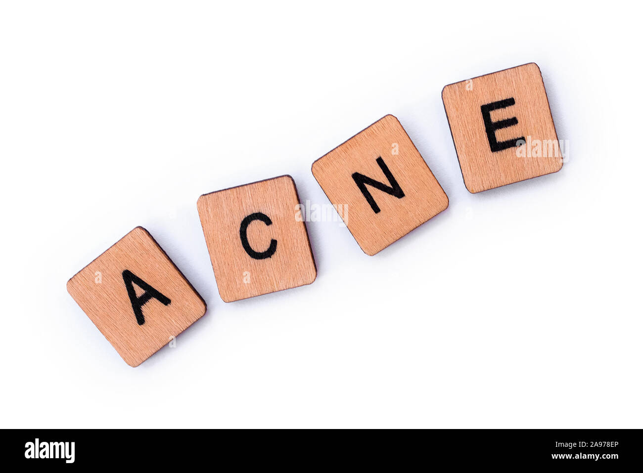 The word ACNE, spelt with wooden letter tiles over a white background ...