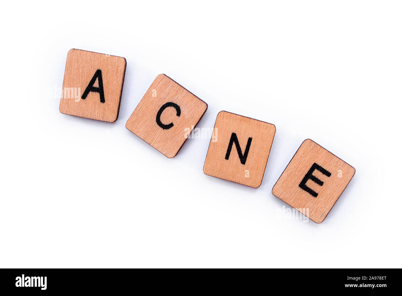 The word ACNE, spelt with wooden letter tiles over a white background ...