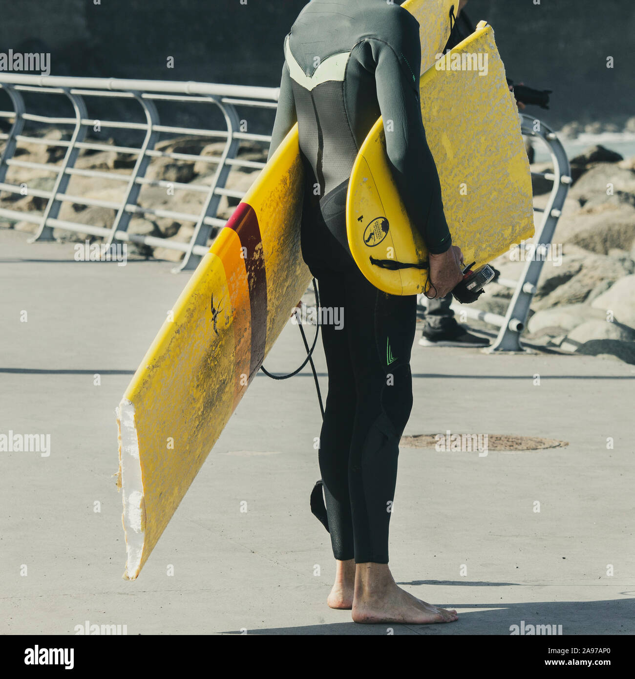 Surfer carrying broken surfboard Stock Photo - Alamy