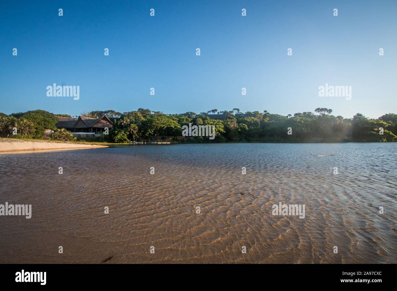 Traditional buildings in a forest by a lagoon on the Swahili Coast ...