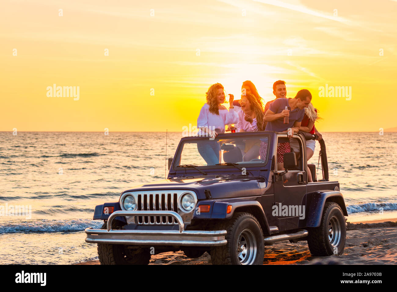 Young group having fun on the beach drink beer and dancing in a ...