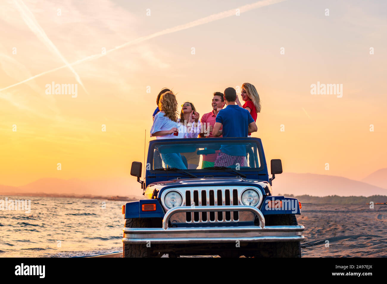 Young group having fun on the beach drink beer and dancing in a ...