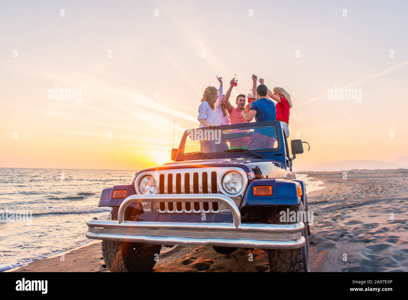 Young group having fun on the beach drink beer and dancing in a ...