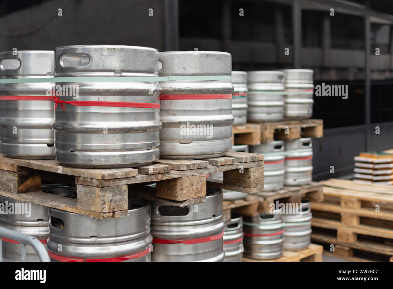 Stock of steel beer kegs on the wooden palettes. Many steel beer ...
