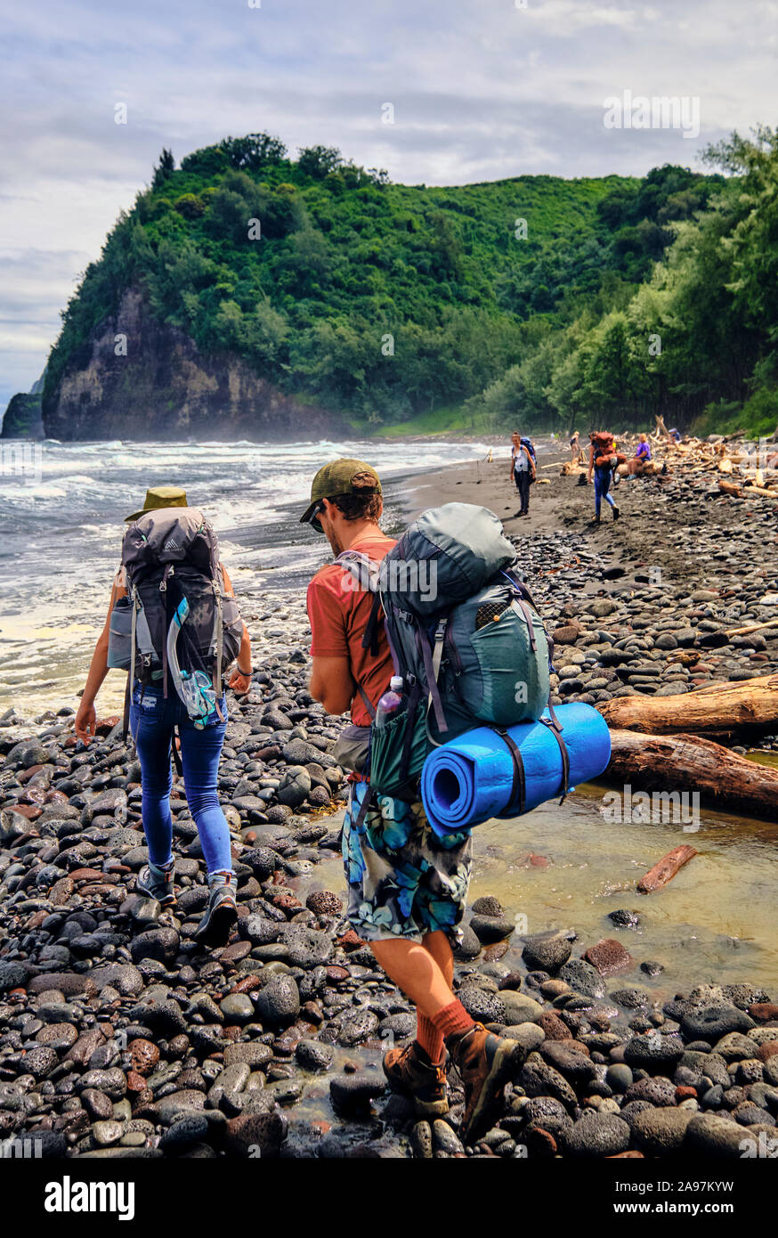 Backpackers beach hiking along the Pacific Ocean in the Pololu Valley ...