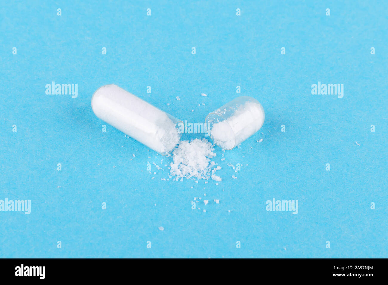 one open capsule of nutritional supplement msm, sulfur, on blue ...