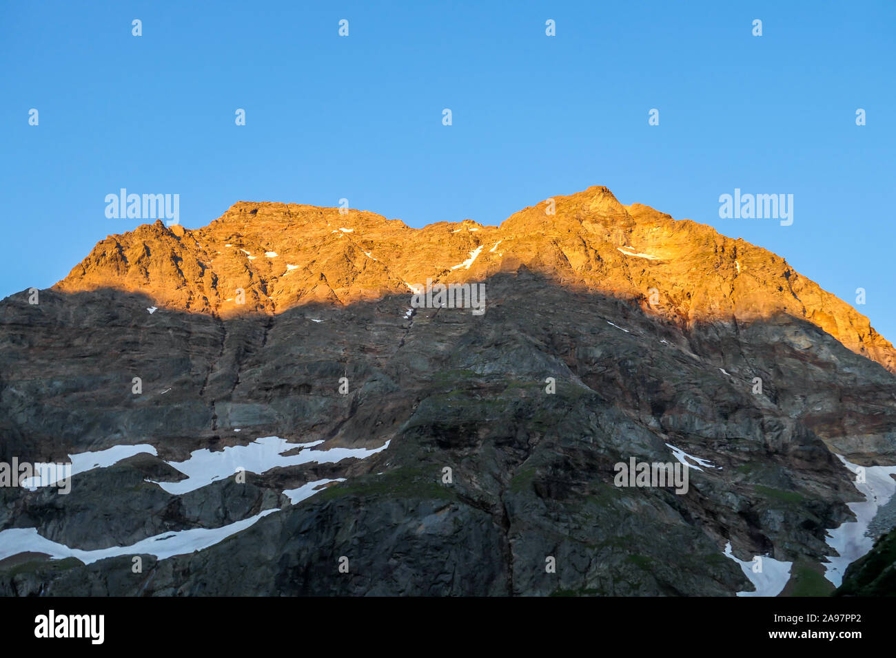 First sunbeams of the day toughing the massive, sharp stony mountain ...