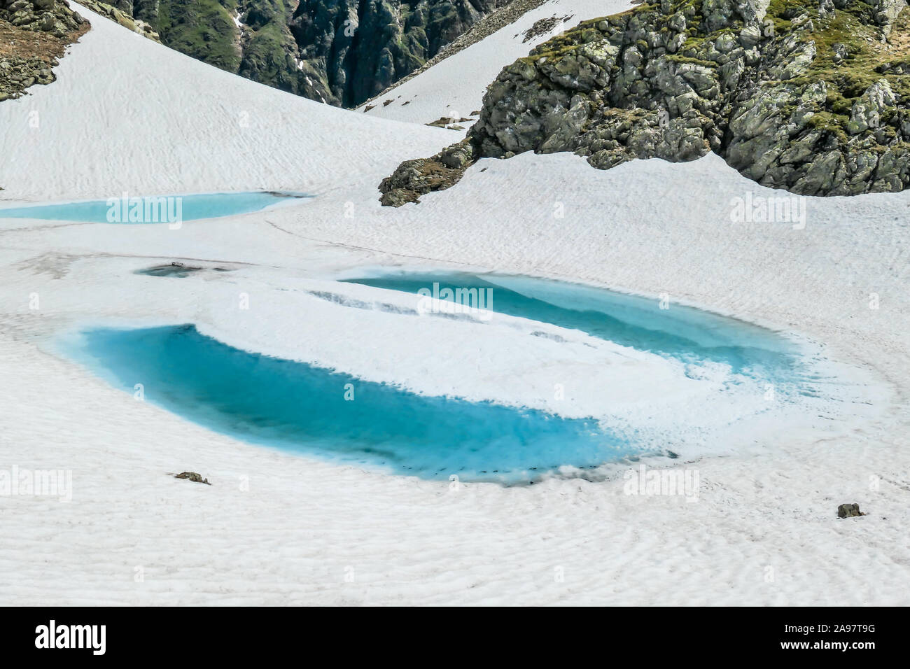 A view on a ice-frozen alpine lake. The ice shines in many different ...