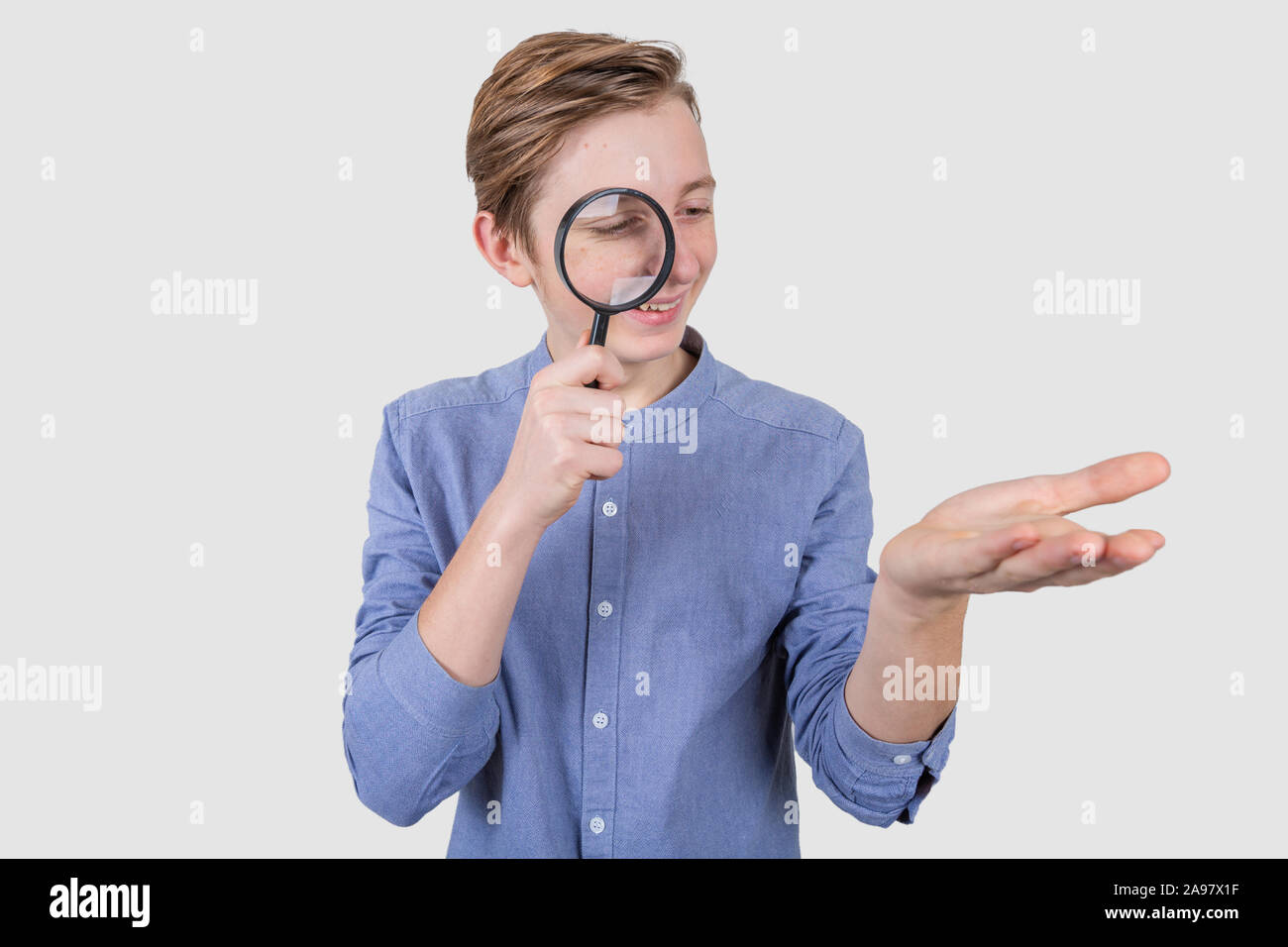 Smiling Teenager with Magnifying Glass looking at something imaginary ...