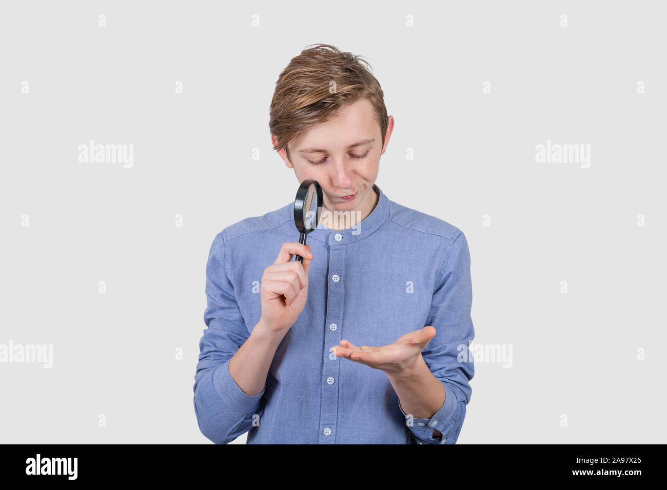 Perplexed tennager with magnifying glass looking at something imaginary ...