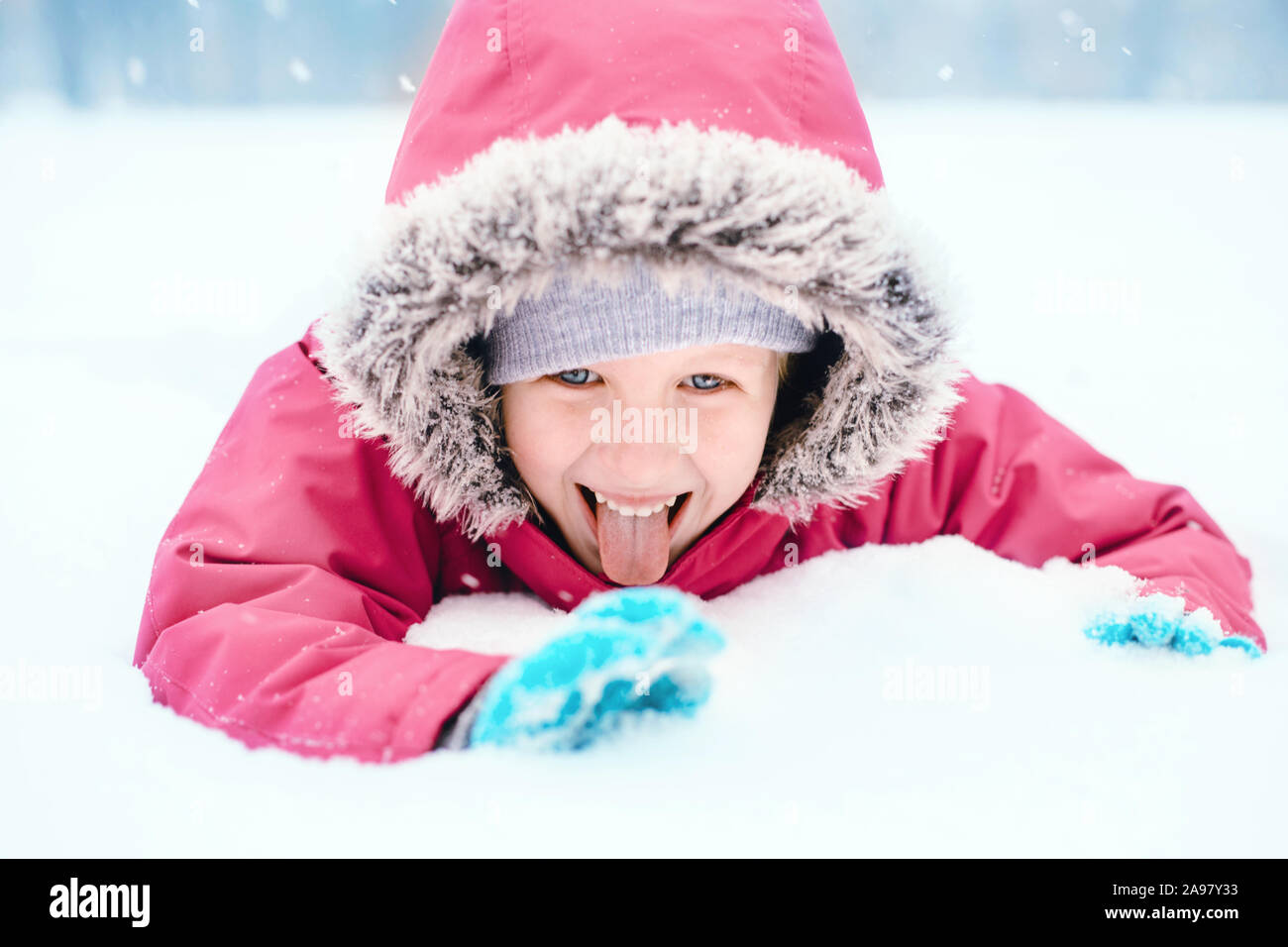 Cute adorable funny Caucasian excited girl child eating licking snow ...