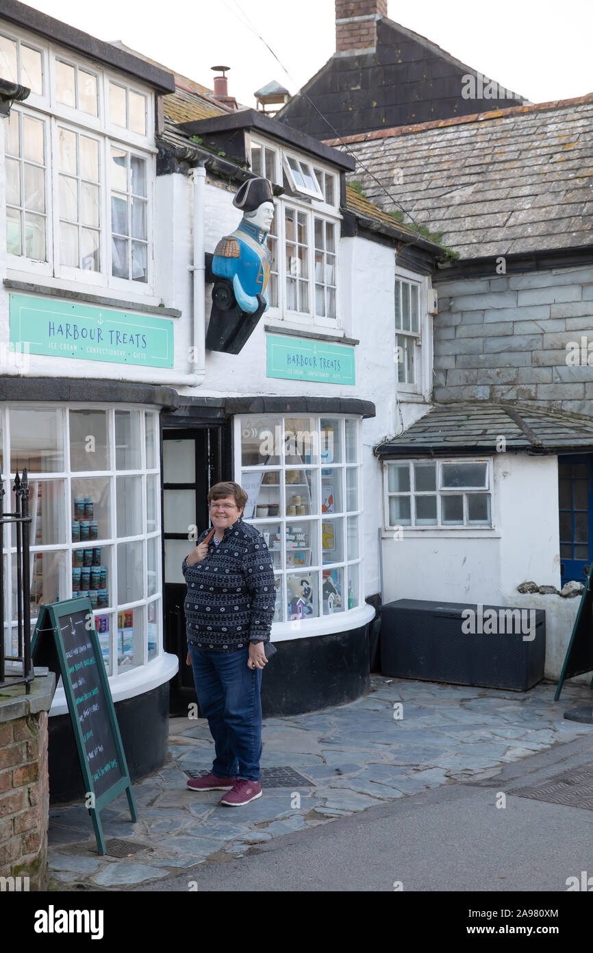 A lady stands outside the famous chemist shop in Port Isaac, Cornwall ...