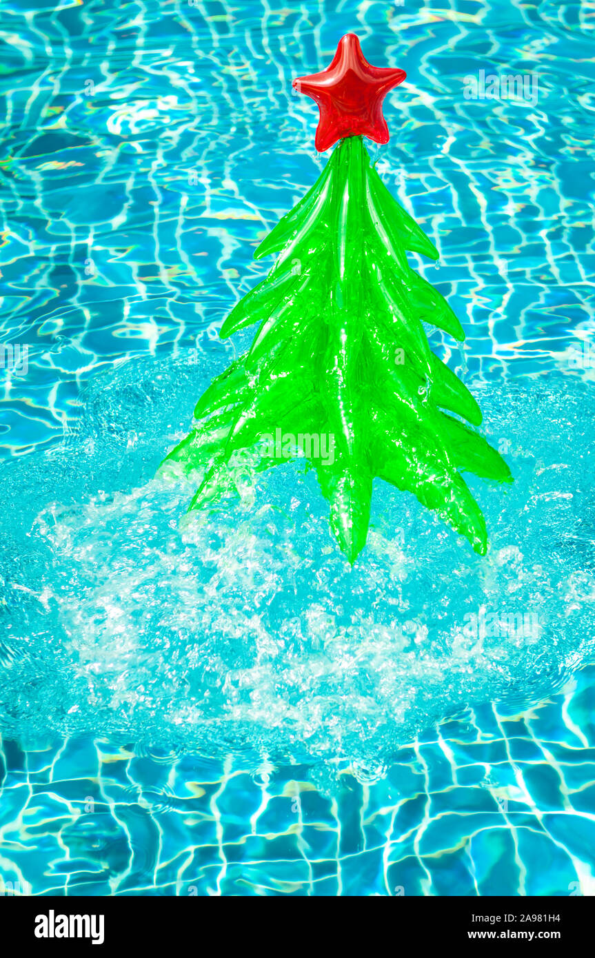 Inflatable Christmas tree splashing out of sparkling blue swimming pool ...
