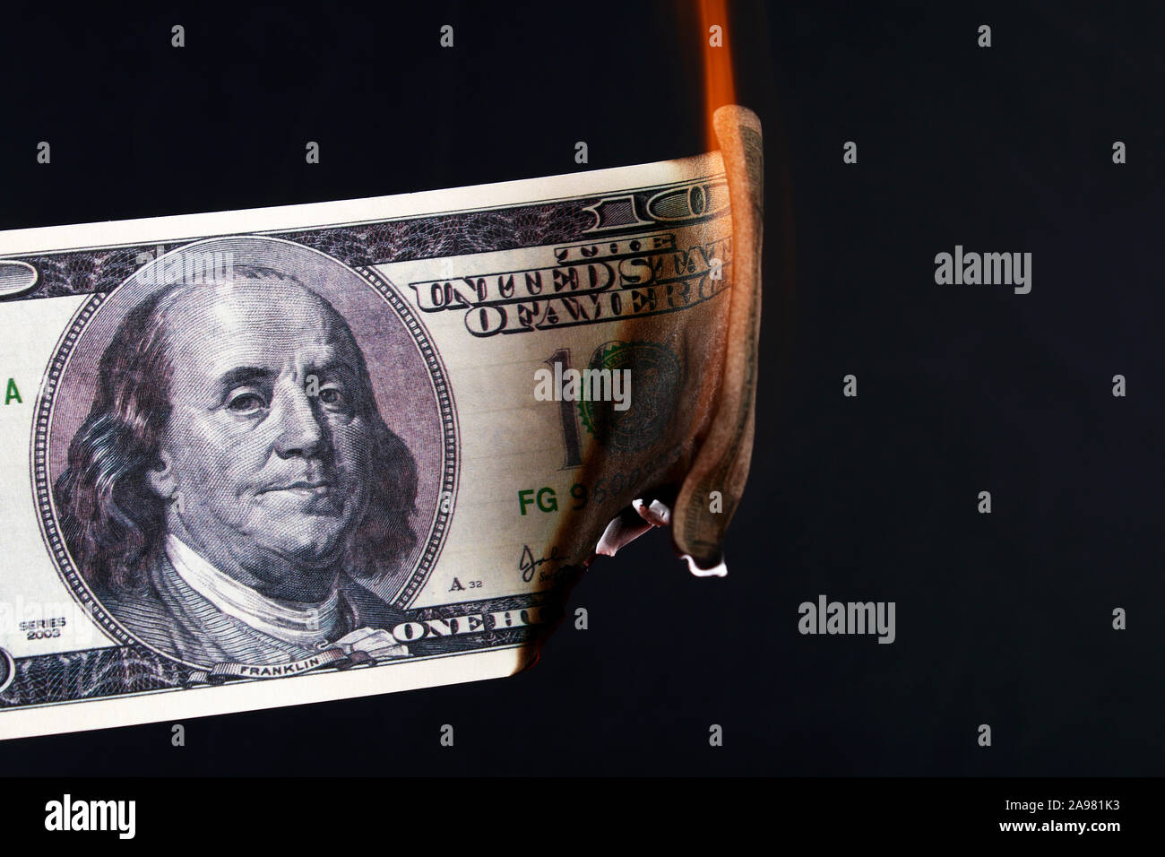 one hundred American dollar burning in fire flame on black paper ...