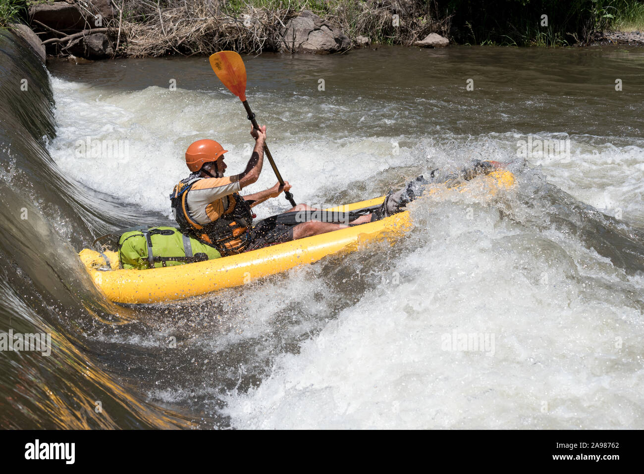 Paddling an inflatable kayak over a weir on the Donner and Blitzen ...