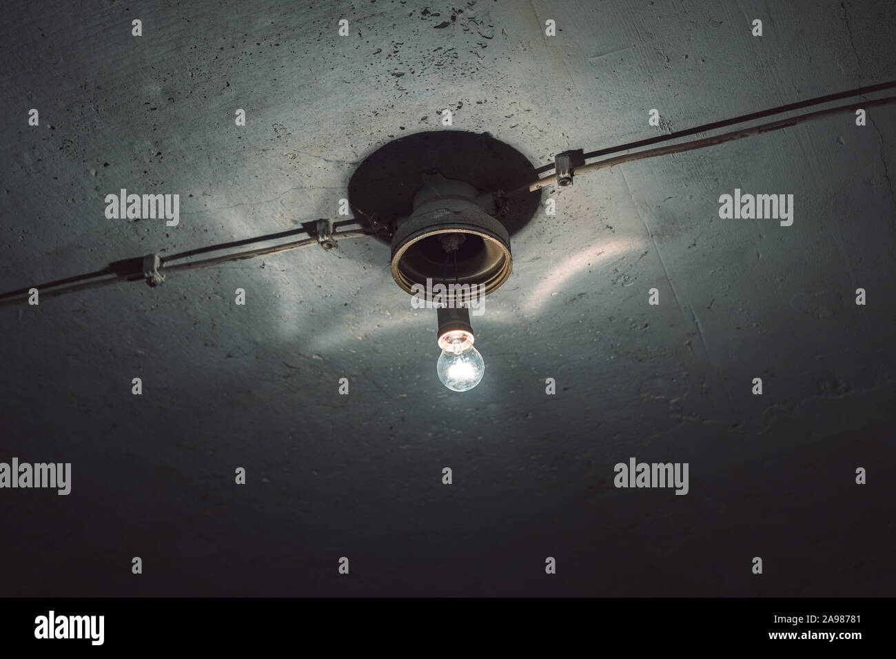Basement light bulb on concrete ceiling, low angle view Stock Photo - Alamy