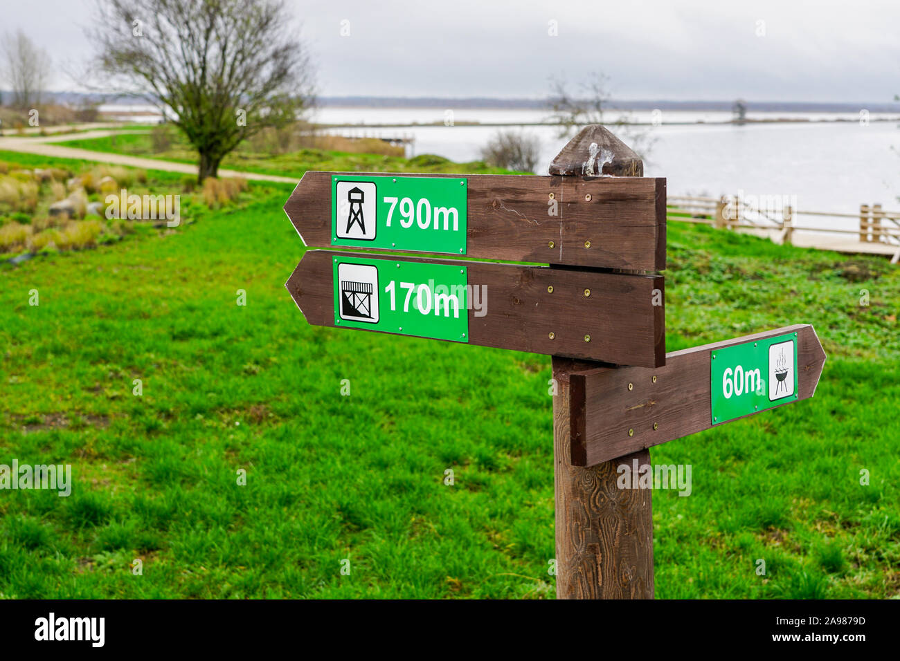 wooden direction indicator in the park with pictograms and distance ...