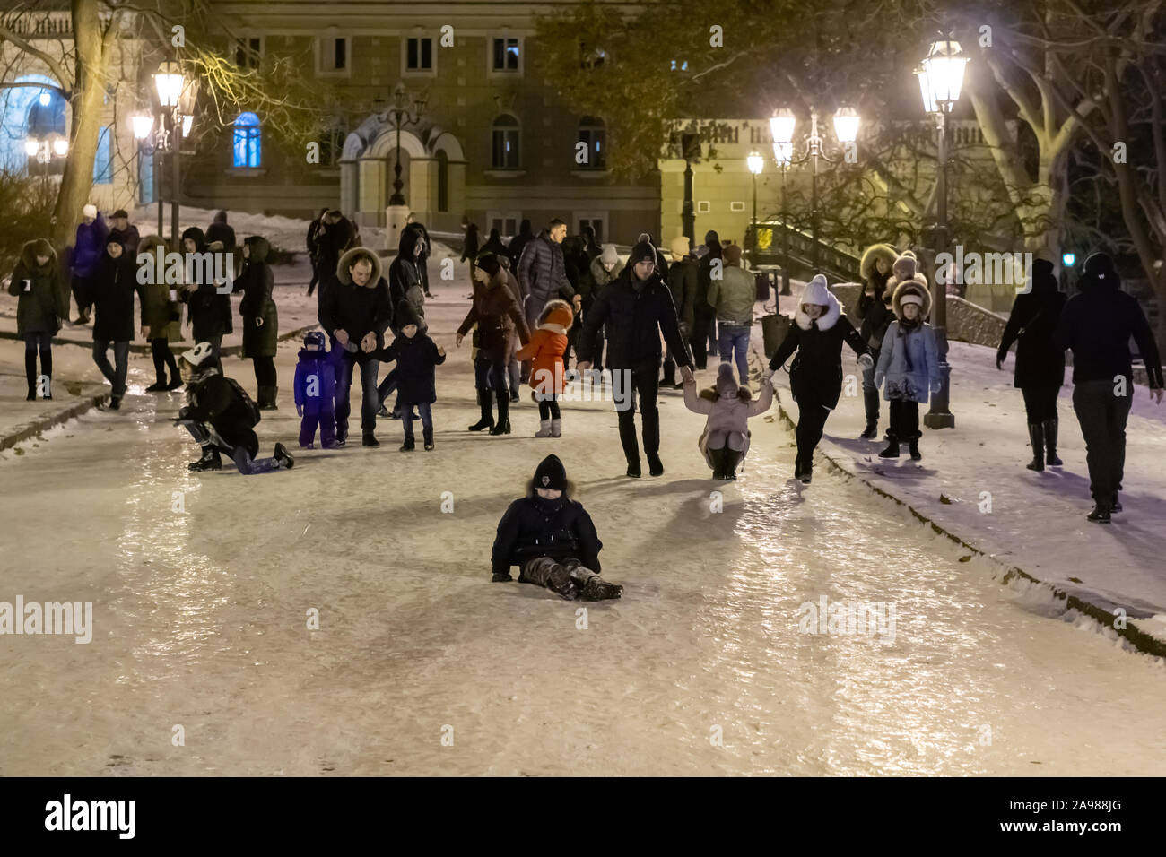 On an improvised ice slide, the inhabitants of the city ride on ice ...