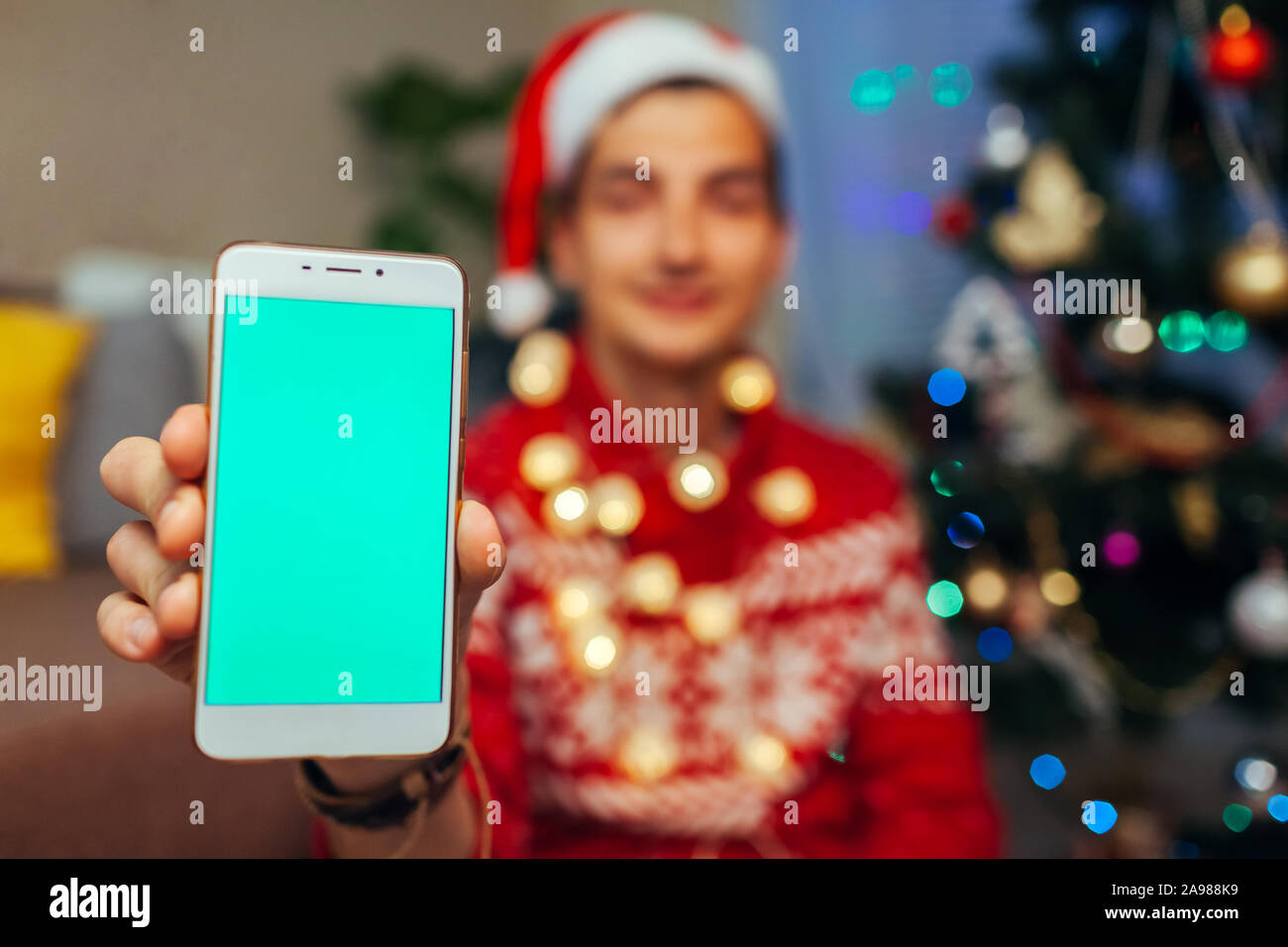 Smartphone for Christmas. Man holding phone with green screen as New ...