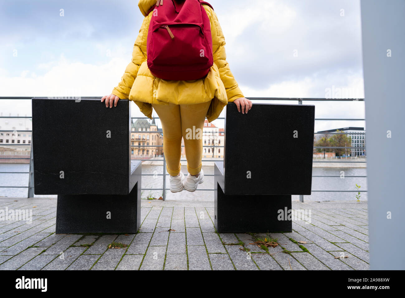 A girl in a yellow jacket and leggings with a red backpack Stock Photo ...