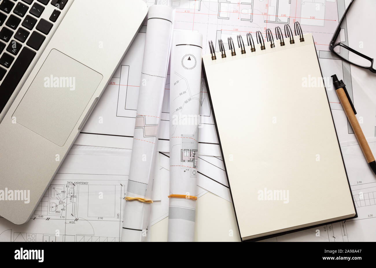 Architect engineer office desk. Blueprint plans, blank notepad and a ...