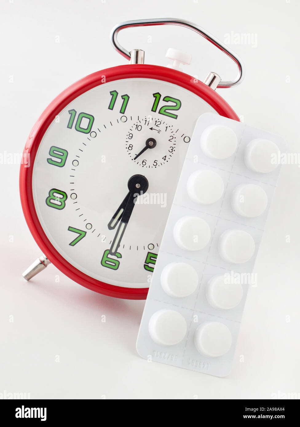 Alarmclock and medicine against white background Stock Photo - Alamy