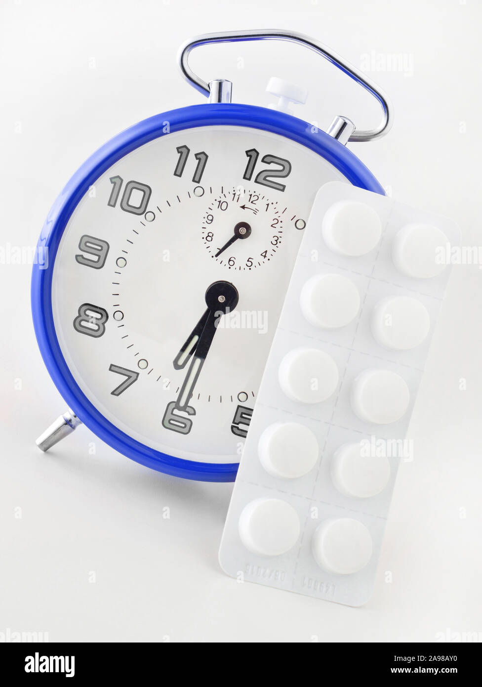 Alarmclock and medicine against white background Stock Photo - Alamy
