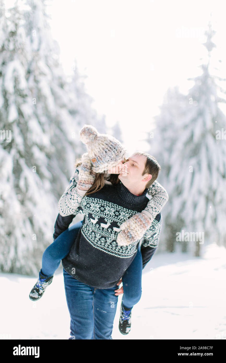 Happy winter travel couple. Man giving woman piggyback ride on winter ...