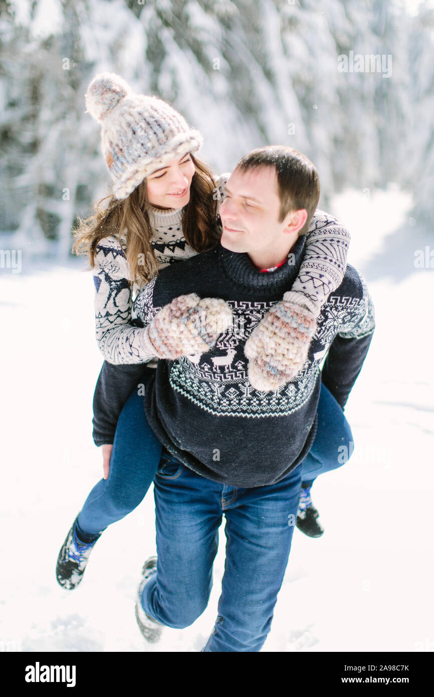 Happy winter travel couple. Man giving woman piggyback ride on winter ...