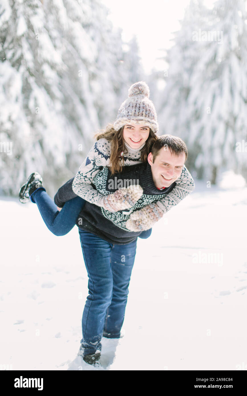 Happy winter travel couple. Man giving woman piggyback ride on winter ...