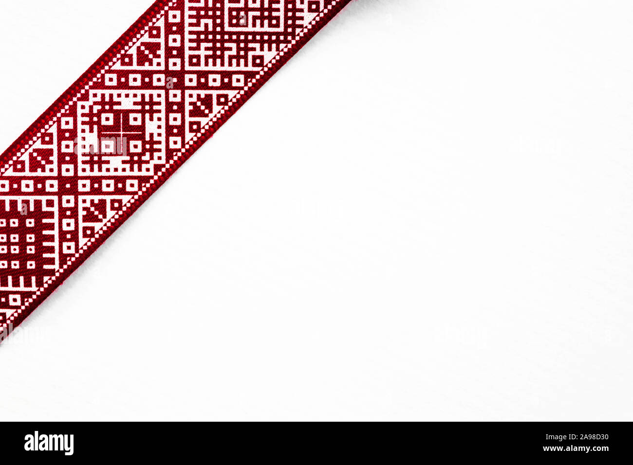 Red and white ribbon with ornament of Latvian signs on white background ...