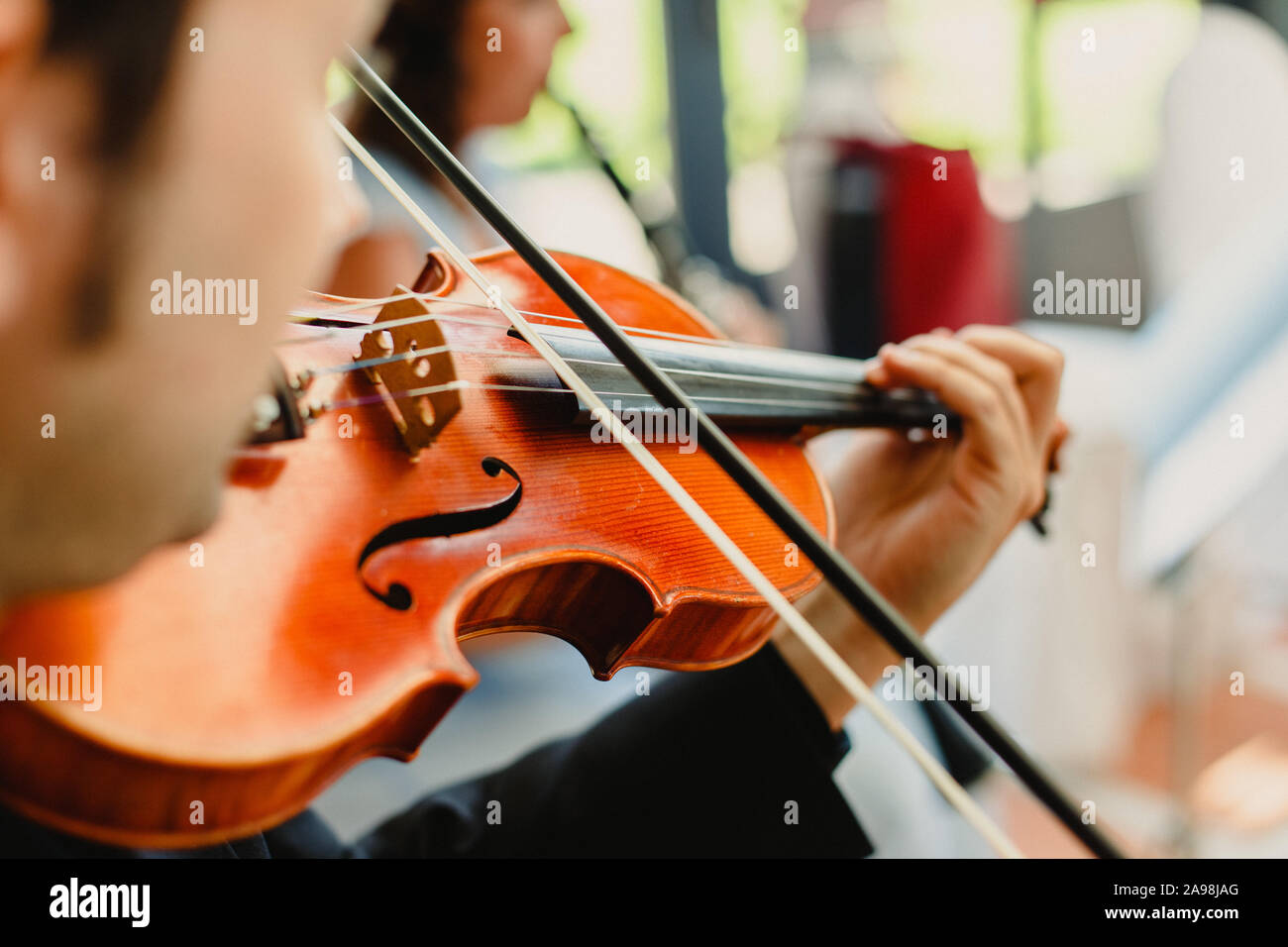 Back view of a violinist performing a piece with his violin, unfocused ...