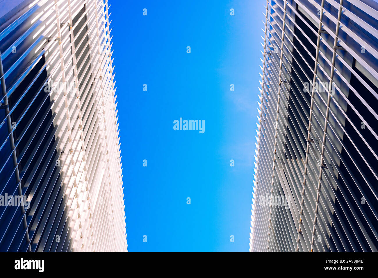 Two buildings converging on a blue sky background in the center Stock ...